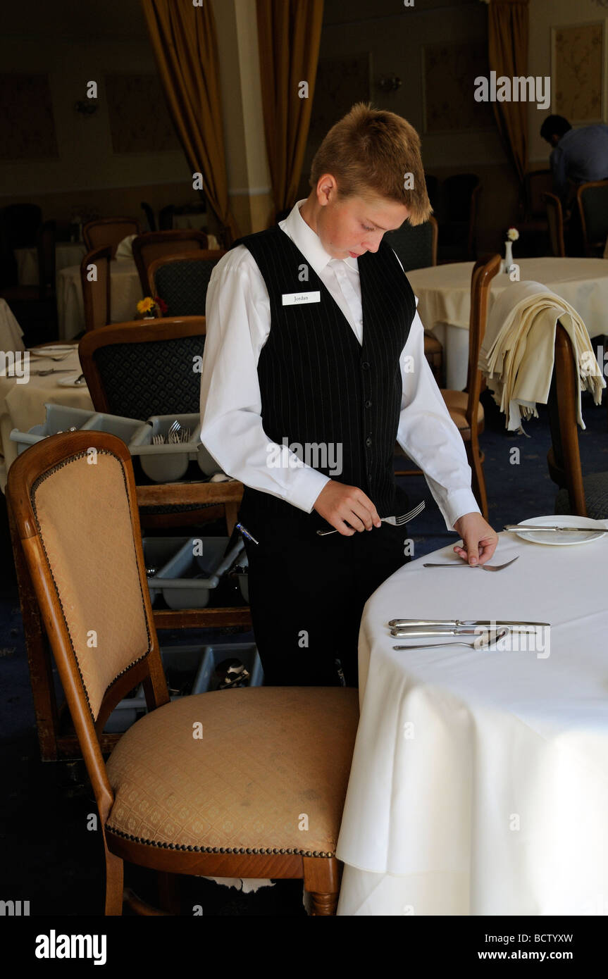 Work experience student laying up a table for lunch service in a hotel ...