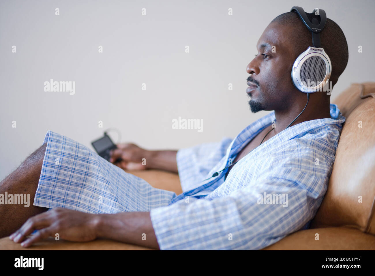 Side profile of a mid adult man listening to an MP3 player Stock Photo ...