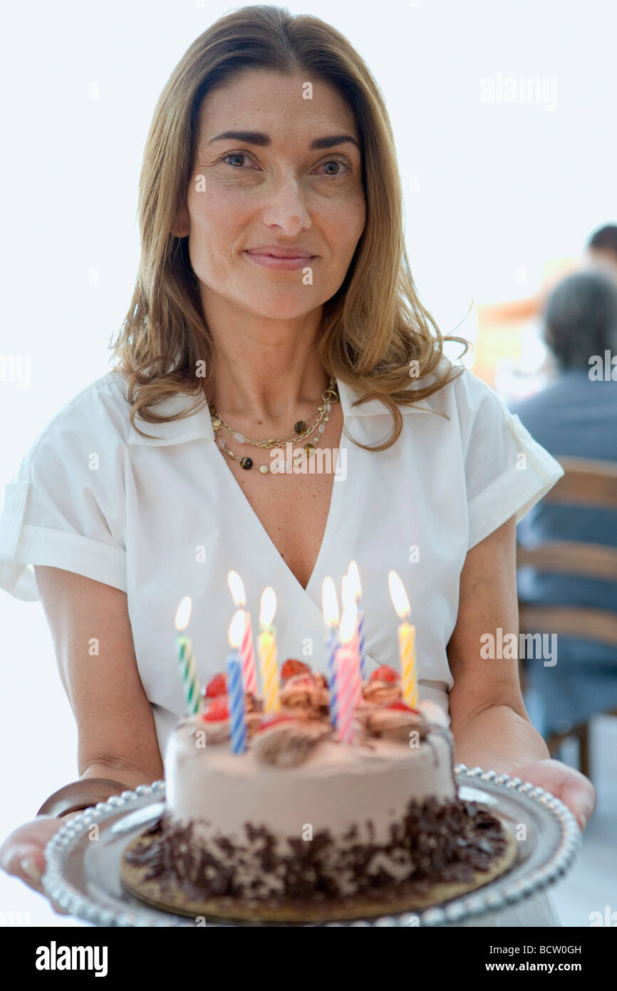 Close-up of a woman standing and holding a birthday cake Stock Photo ...