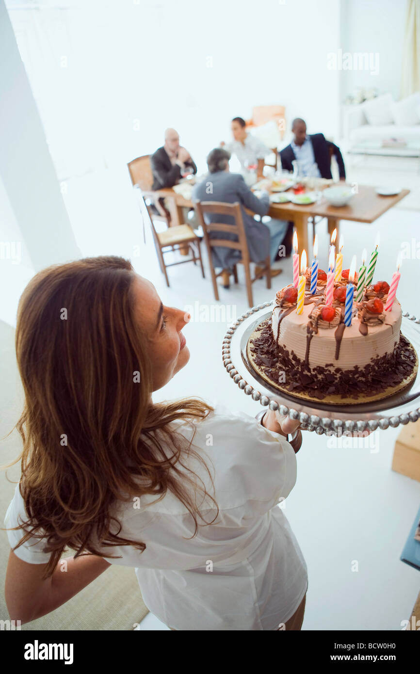 Rear view of a woman carrying a birthday cake to group of friends Stock ...