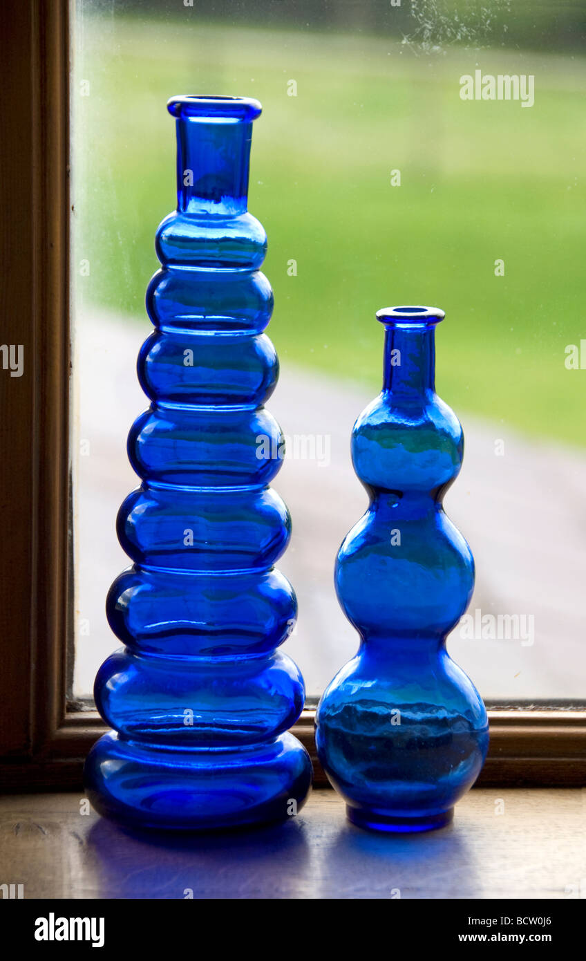 Two blue glass vases standing on window ledge Stock Photo - Alamy