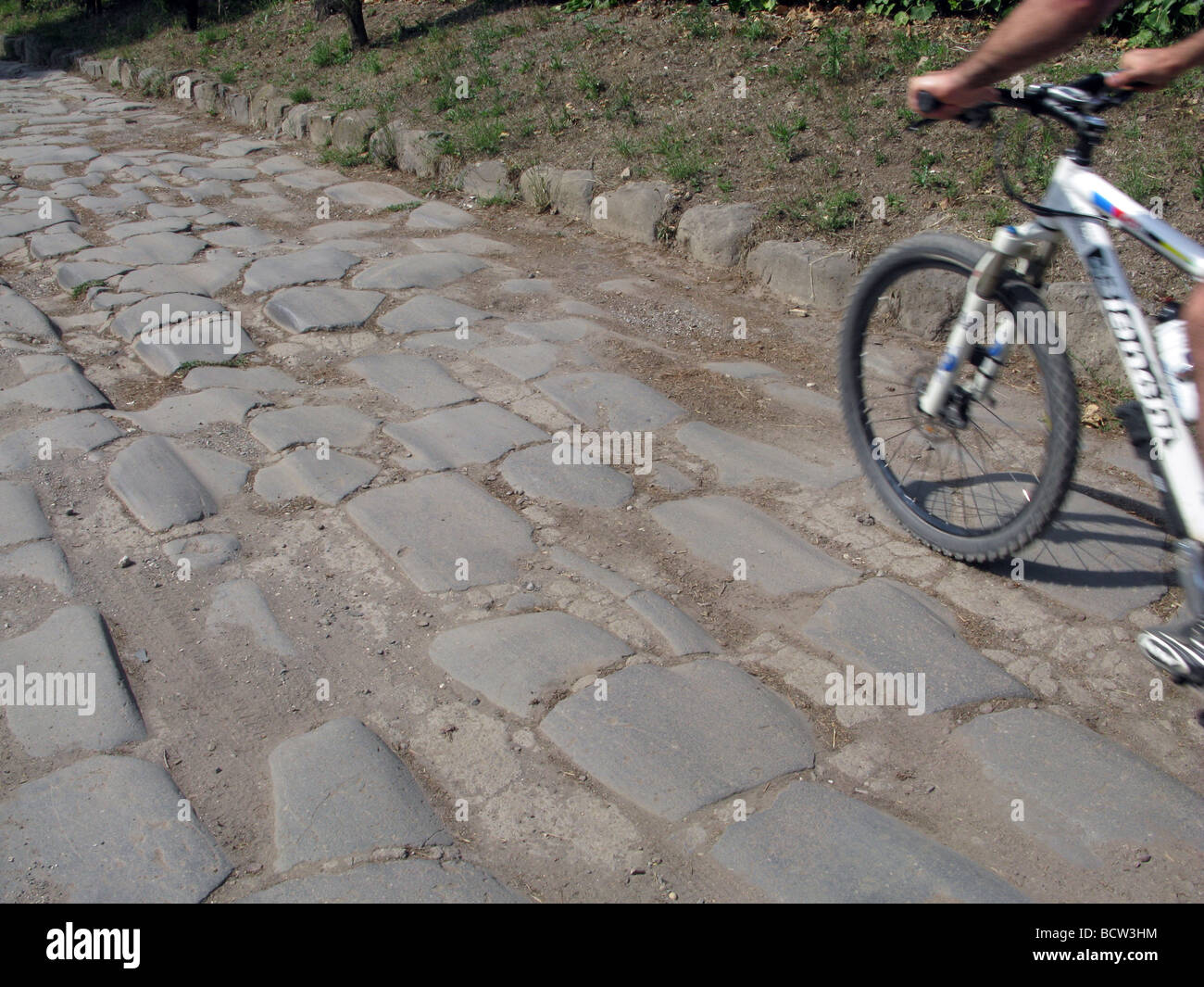 person riding bike on the ancient roman old appian way, rome, italy ...