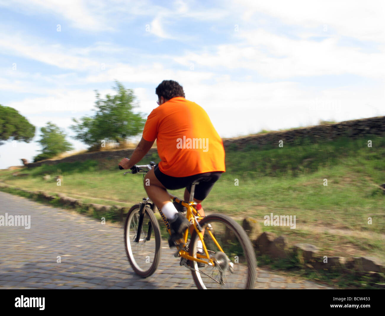 person riding bike on the ancient roman old appian way, rome, italy ...
