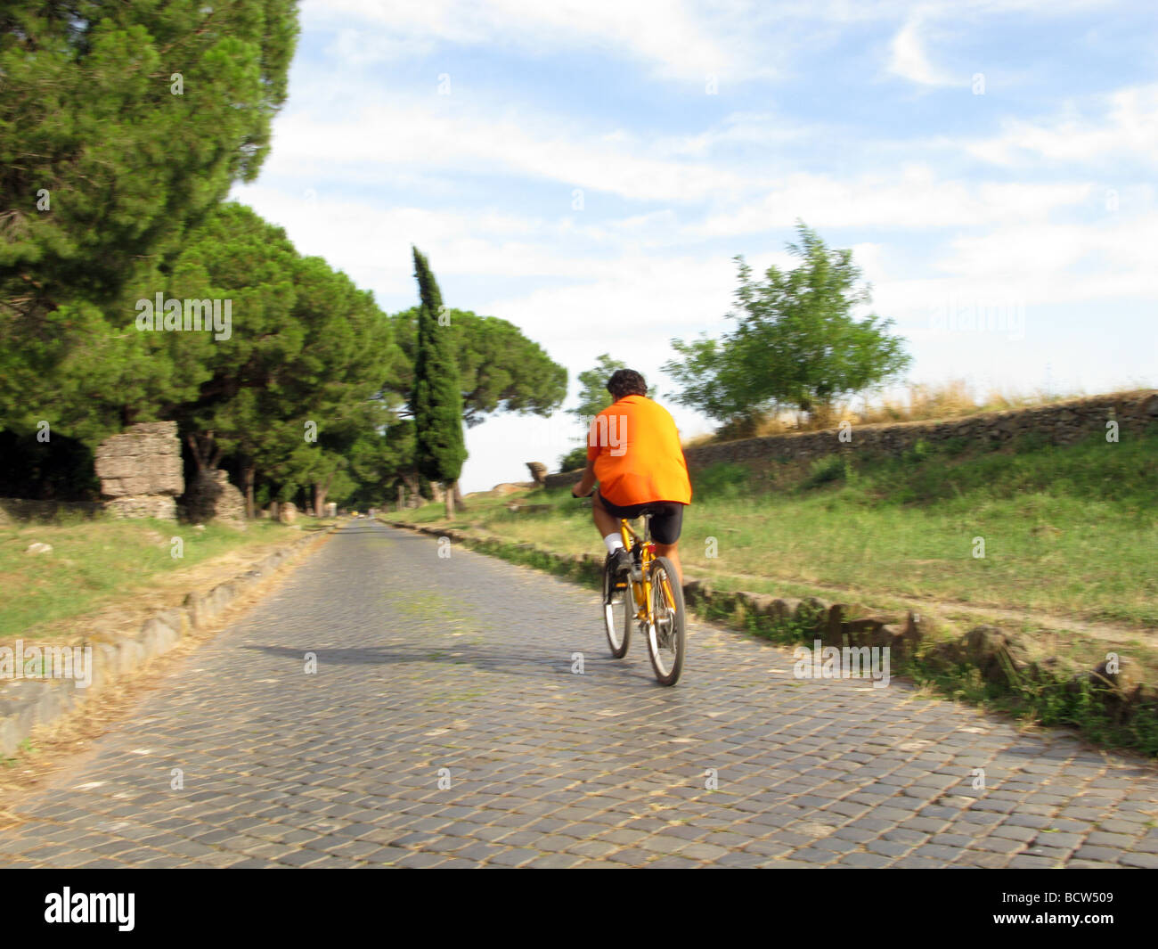 person riding bike on the ancient roman old appian way, rome, italy ...