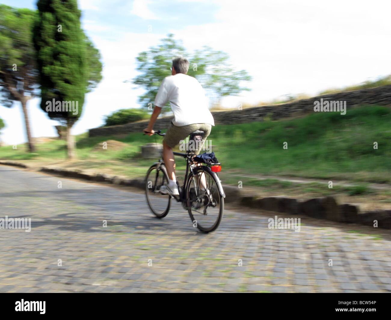 person riding bike on the ancient roman old appian way, rome, italy ...