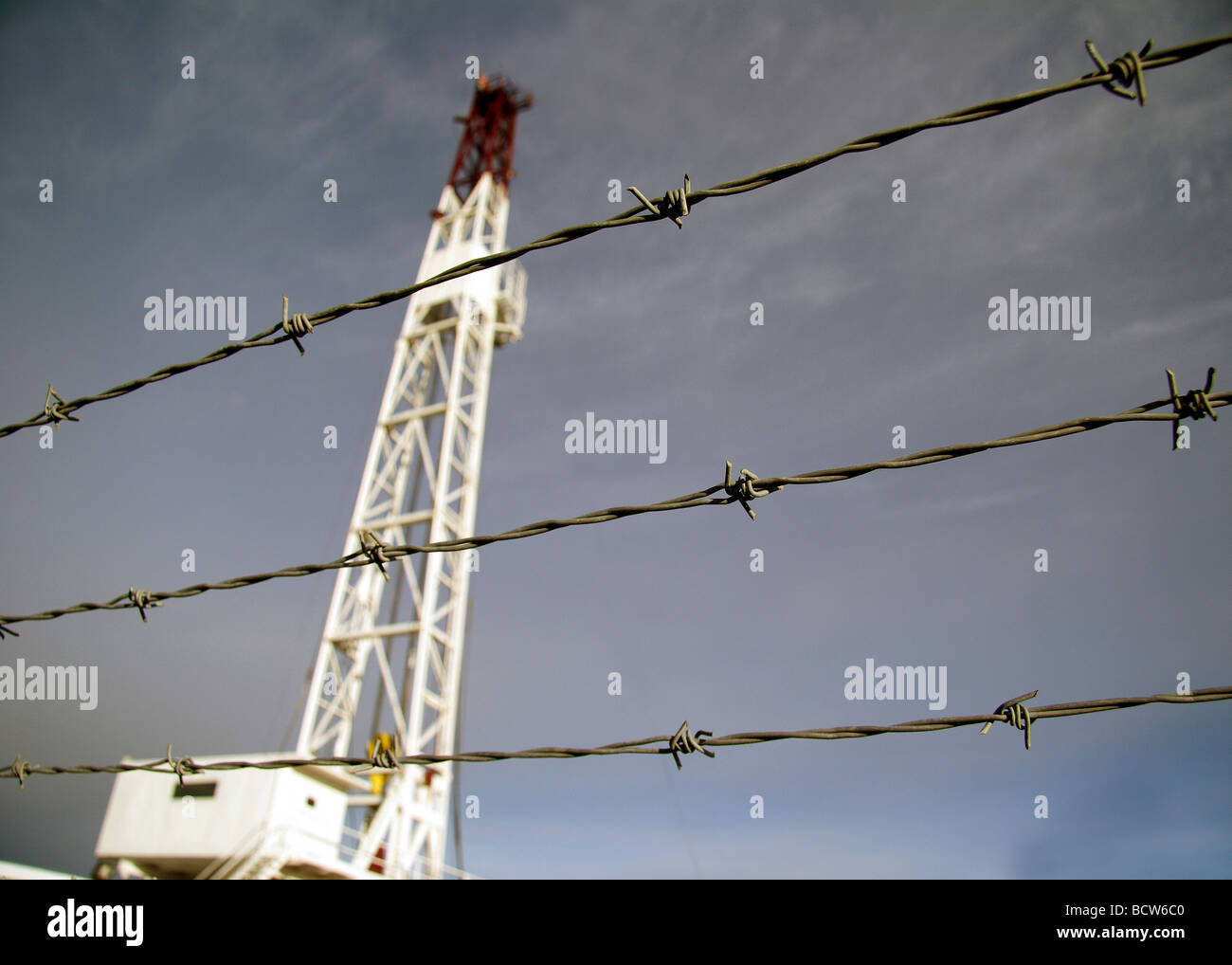 Barbed wire fence with an oil rig in the background Stock Photo - Alamy