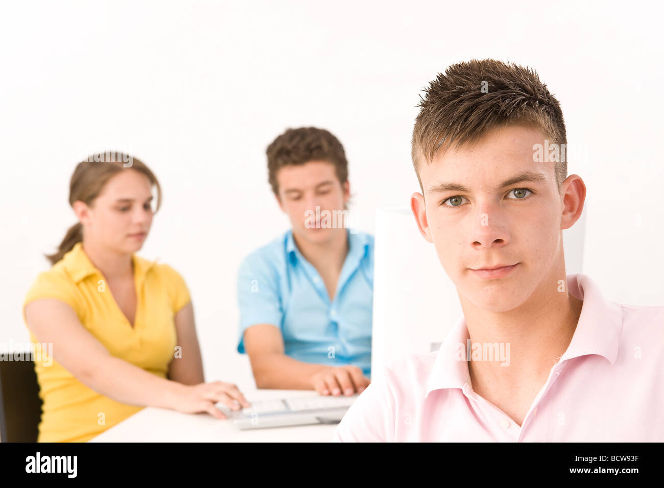 Portrait of a boy, two adolescents working on a computer in the back ...