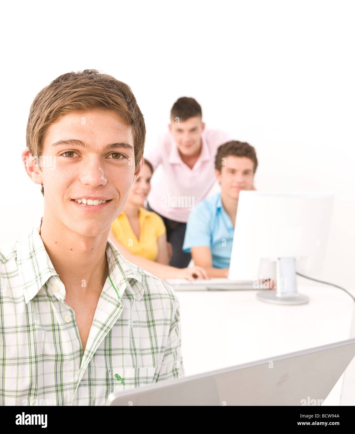 Portrait of a boy, three adolescents working on a computer in the back ...