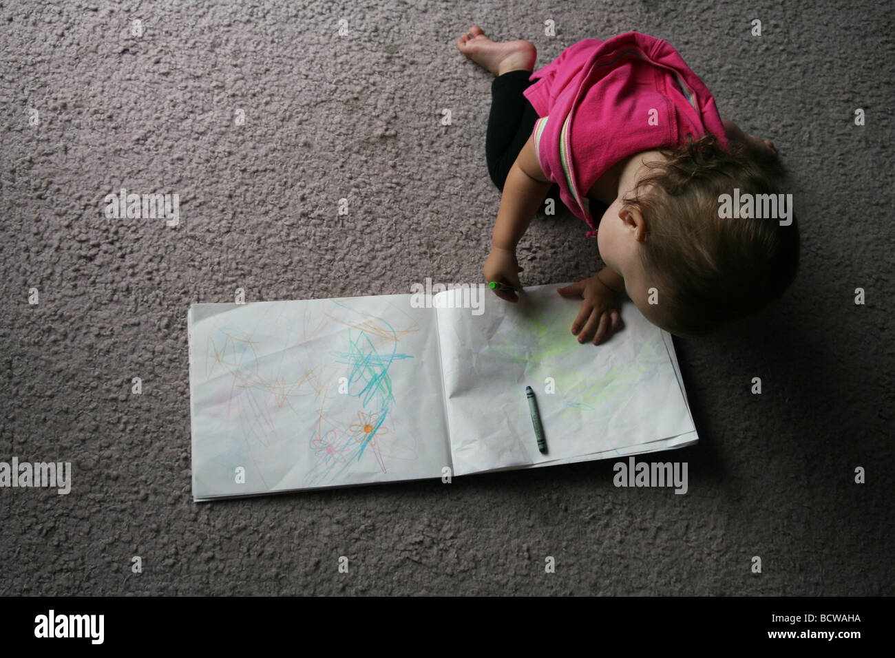 A small child coloring on paper with crayons, as seen from above Stock ...