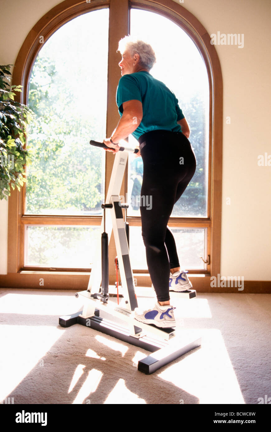 Senior woman exercising on stair climbing machine Stock Photo - Alamy