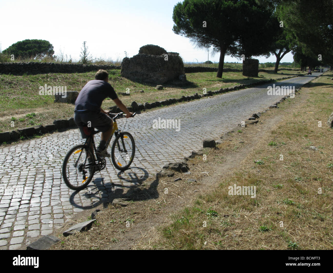 person riding bike on the ancient roman old appian way, rome, italy ...
