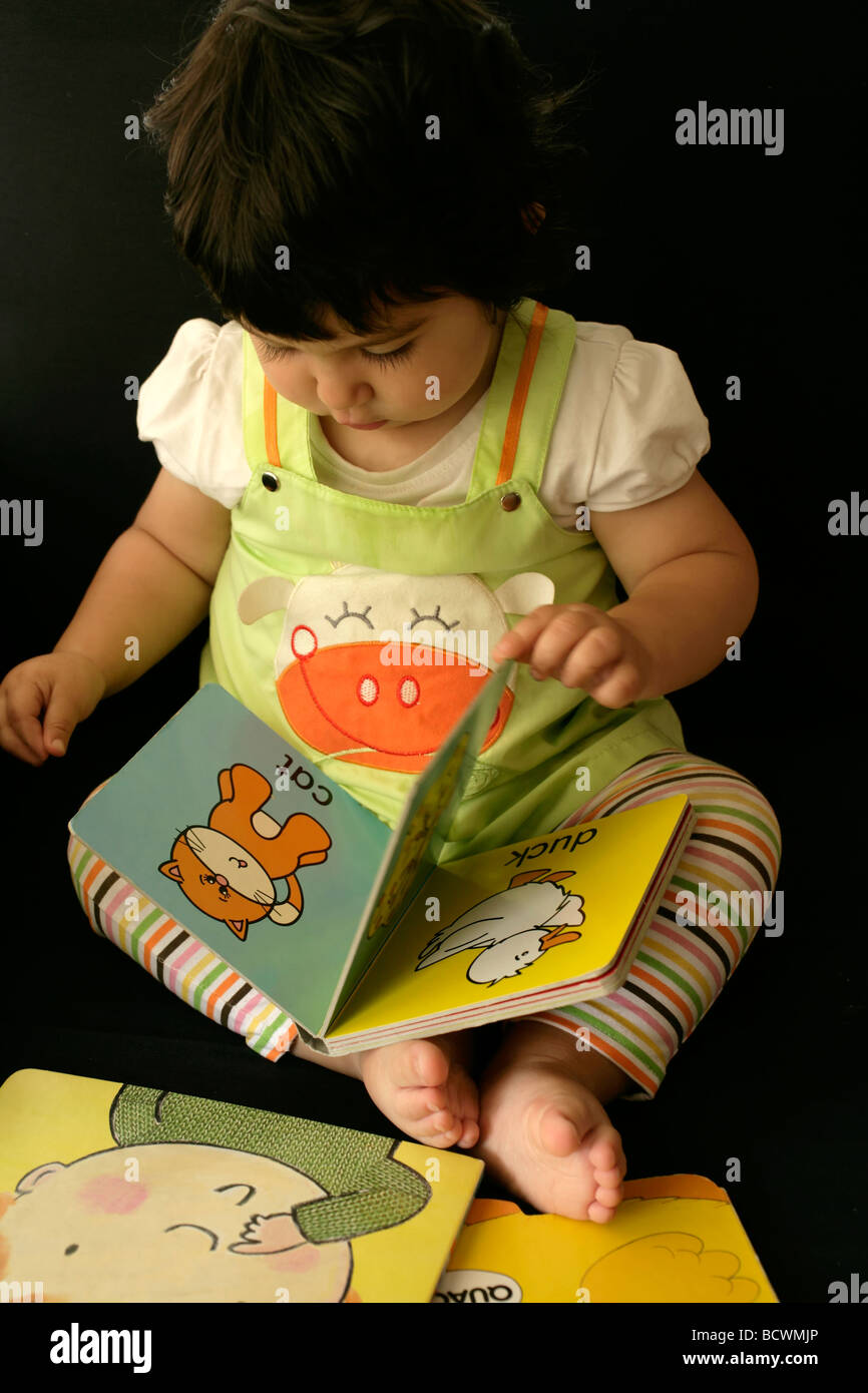 Toddler looking at a book Stock Photo - Alamy