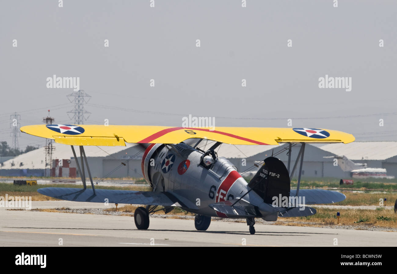 A Grumman F3F-2 biplane taxis on the runway at an airshow. (view from ...