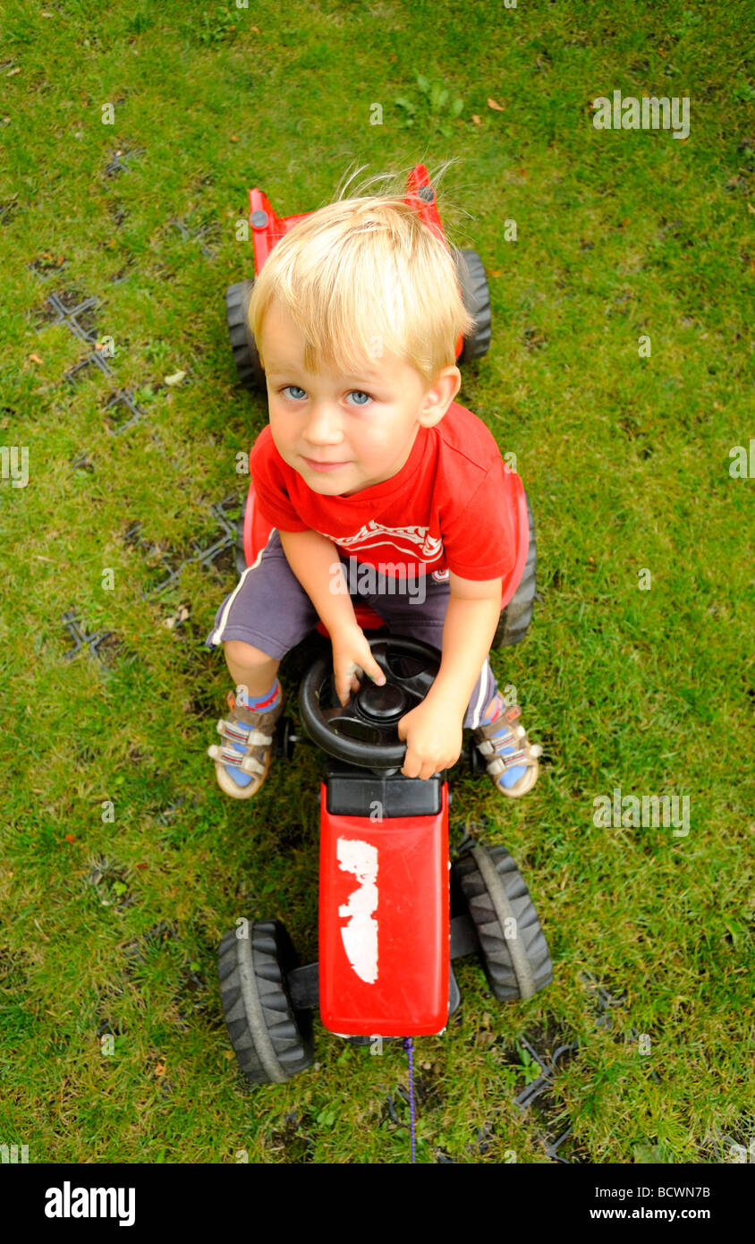 Child blond Boy driving a toy plastic tractor Stock Photo - Alamy