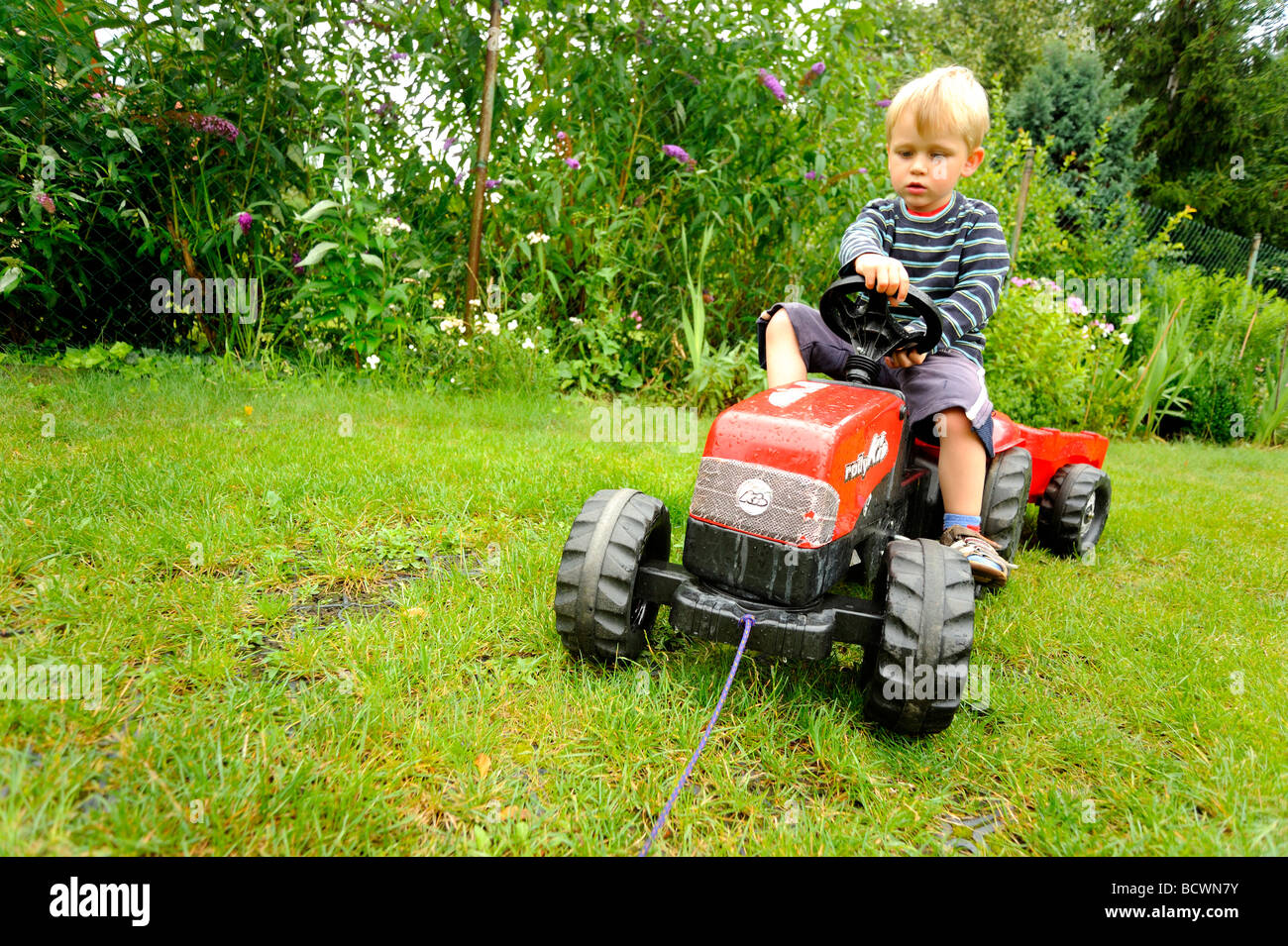 Child blond Boy driving a toy plastic tractor Stock Photo - Alamy