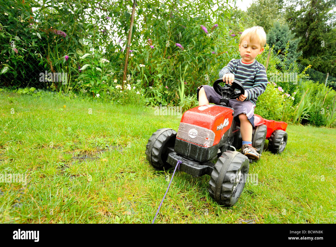 Child blond Boy driving a toy plastic tractor Stock Photo - Alamy
