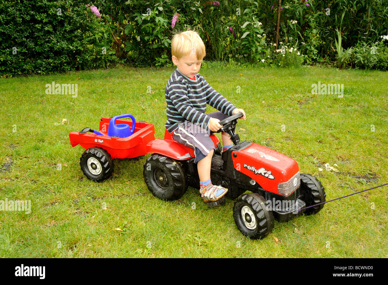Child blond Boy driving a toy plastic tractor Stock Photo - Alamy
