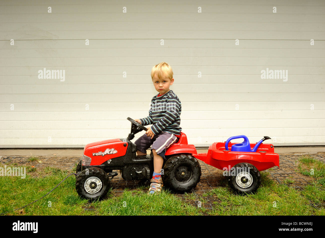 Child blond Boy driving a toy plastic tractor Stock Photo - Alamy