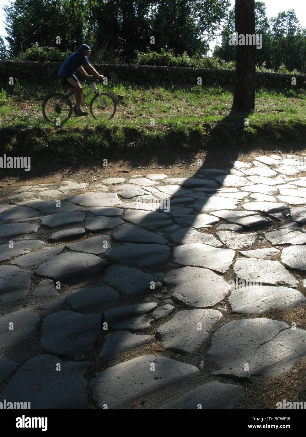 person riding bike on the ancient roman old appian way, rome, italy ...