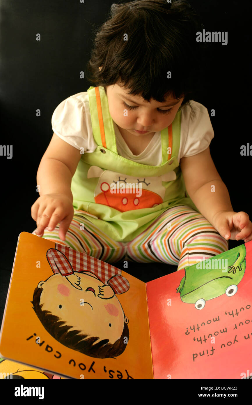 Toddler looking at a book Stock Photo - Alamy