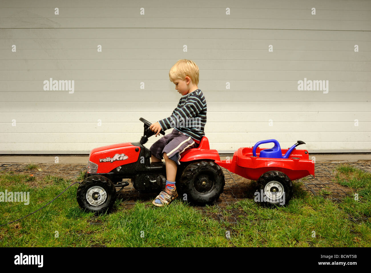 Child blond Boy driving a toy plastic tractor Stock Photo - Alamy