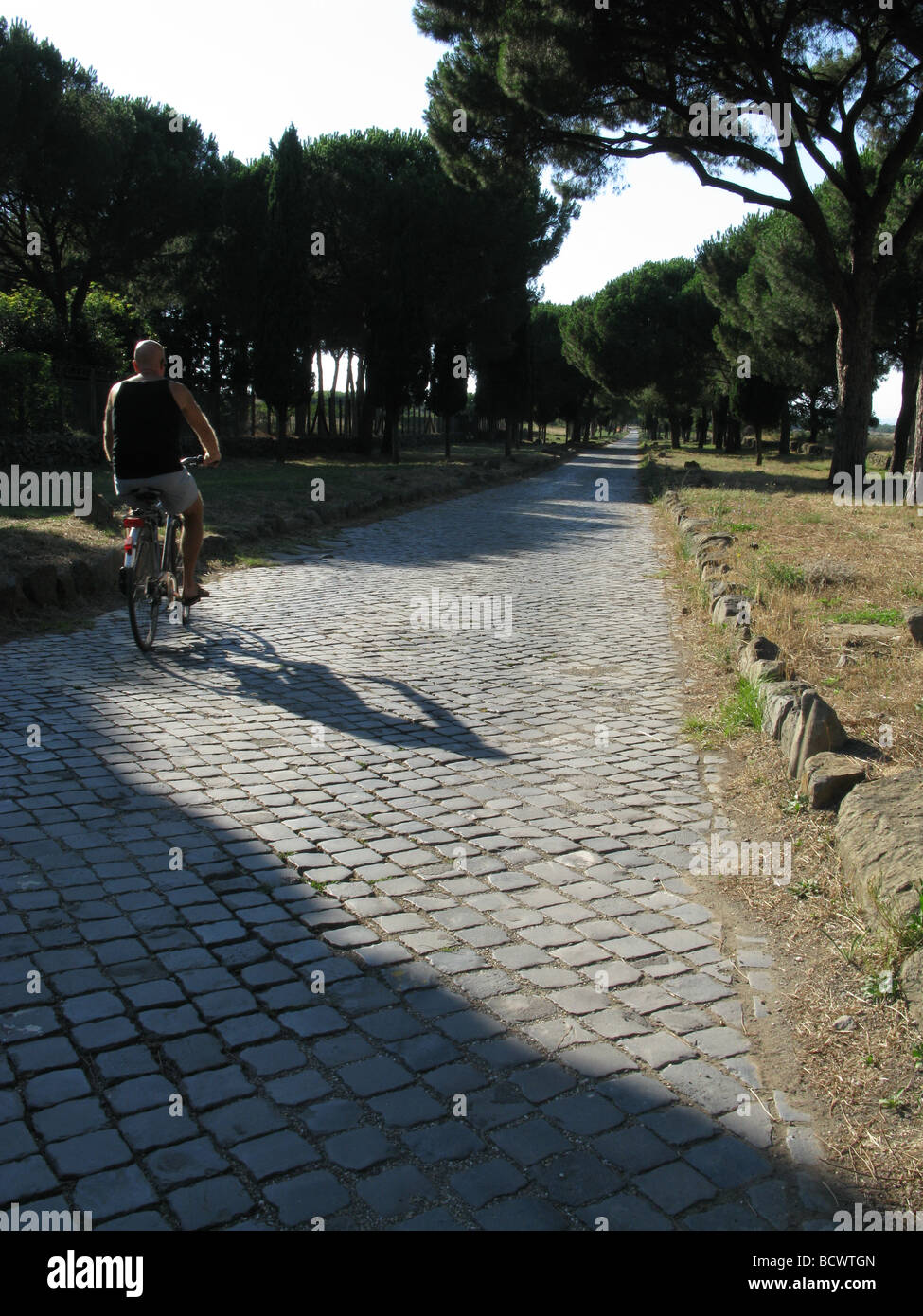 person riding bike on the ancient roman old appian way, rome, italy ...
