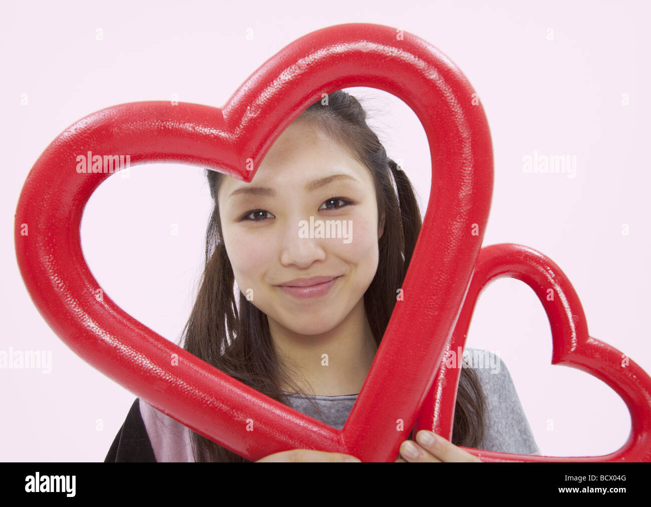 Young woman holding heart shaped objects Stock Photo - Alamy