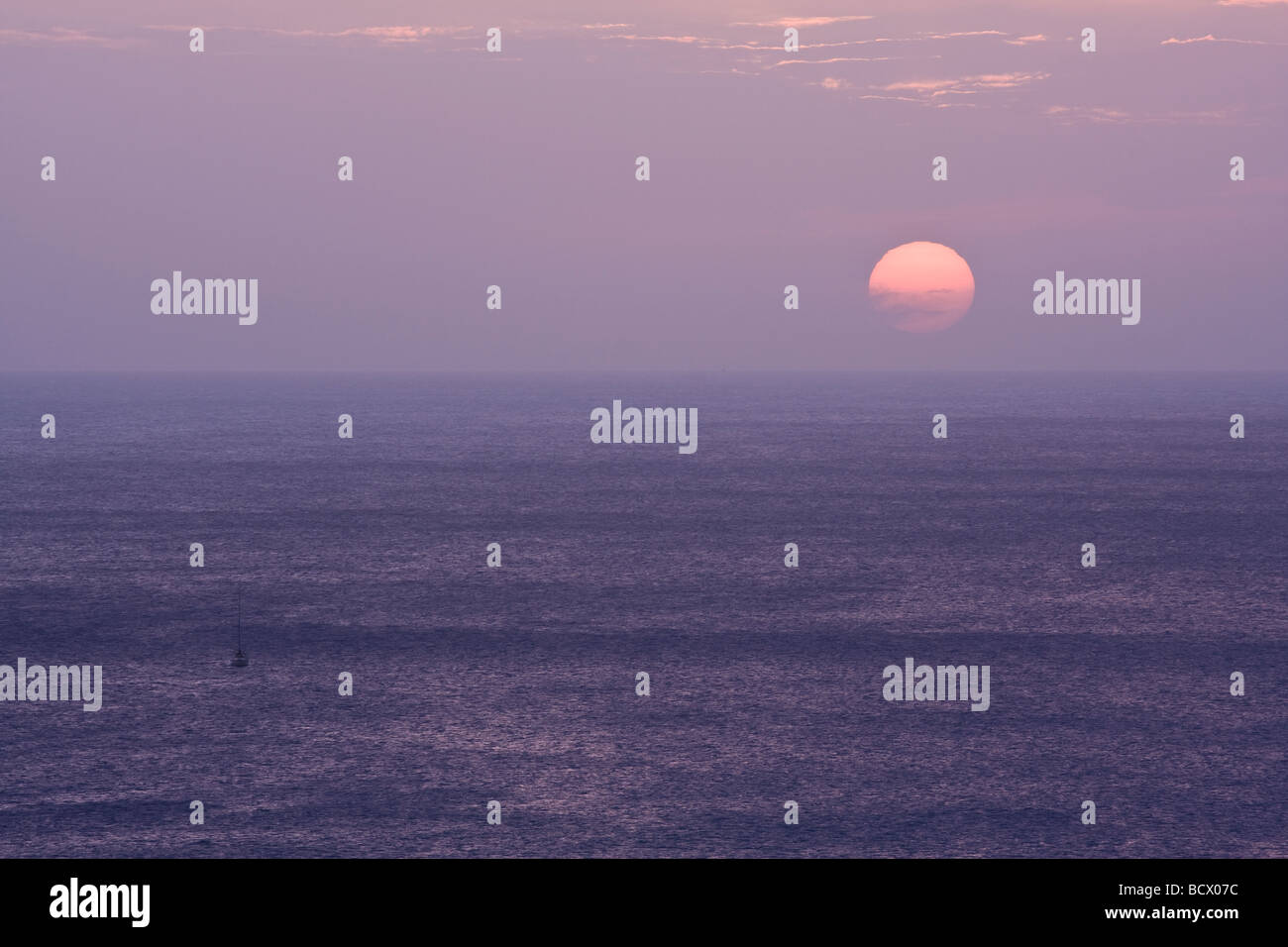 Sun setting close to the horizon. Patterns in the ocean and a small ...