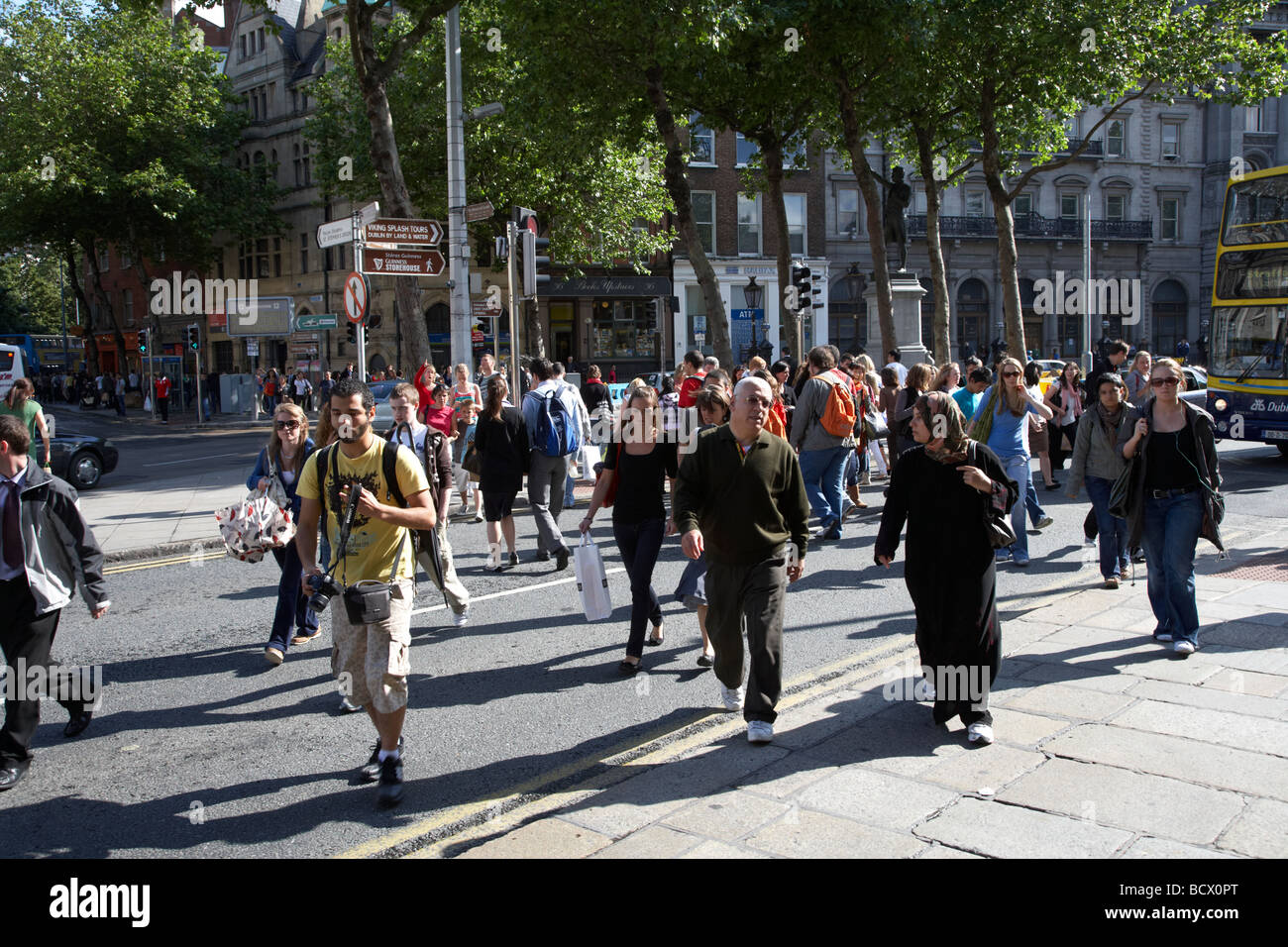 tourists crossing a busy street junction on college green in dublin ...