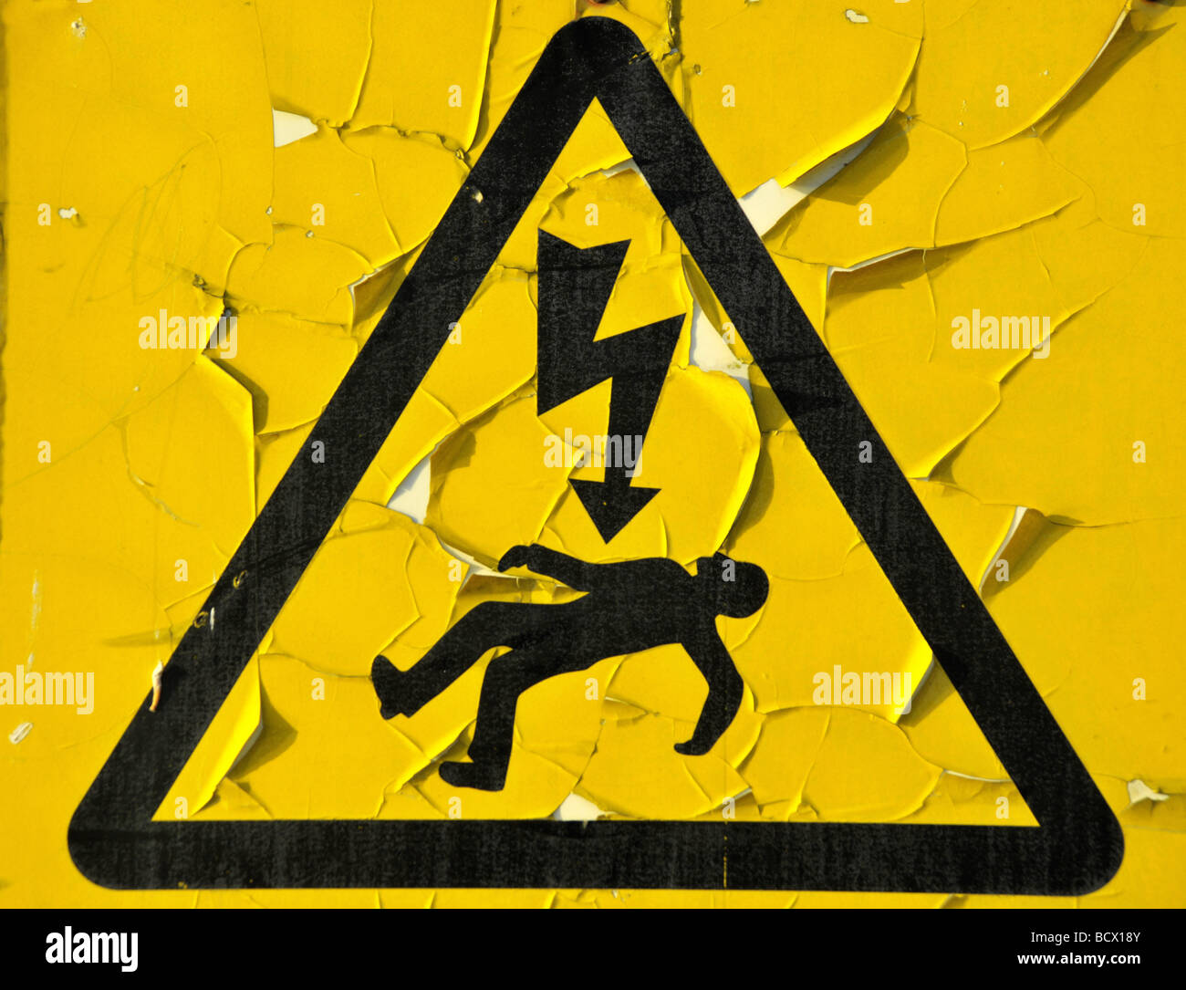 A detail of a peeling warning sign near the base of an electricity pole ...