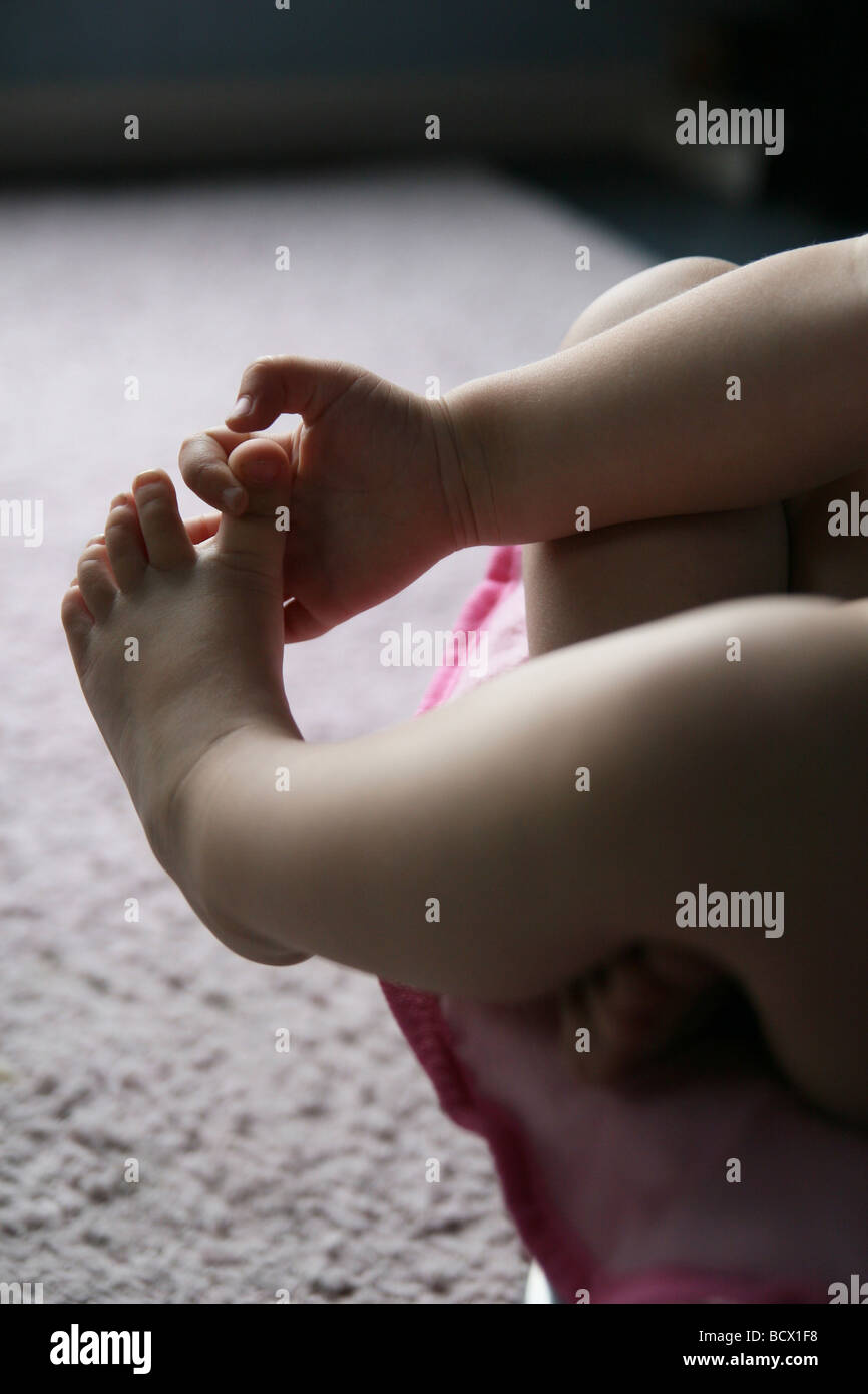 A small child holding her own toe Stock Photo - Alamy