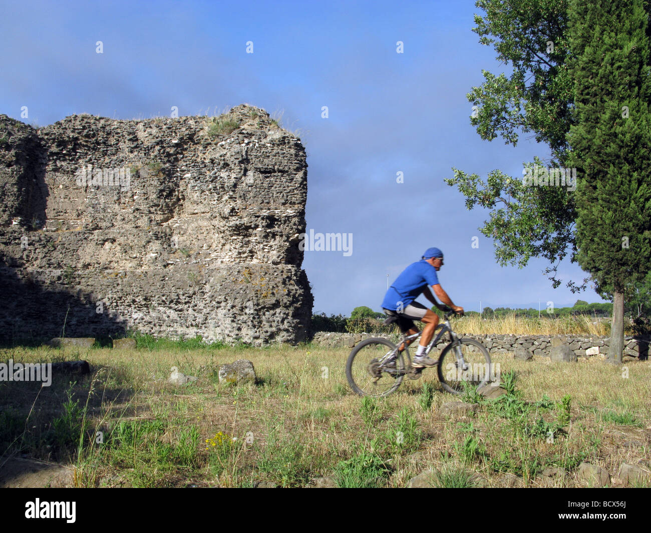 person riding bike on the ancient roman old appian way, rome, italy ...