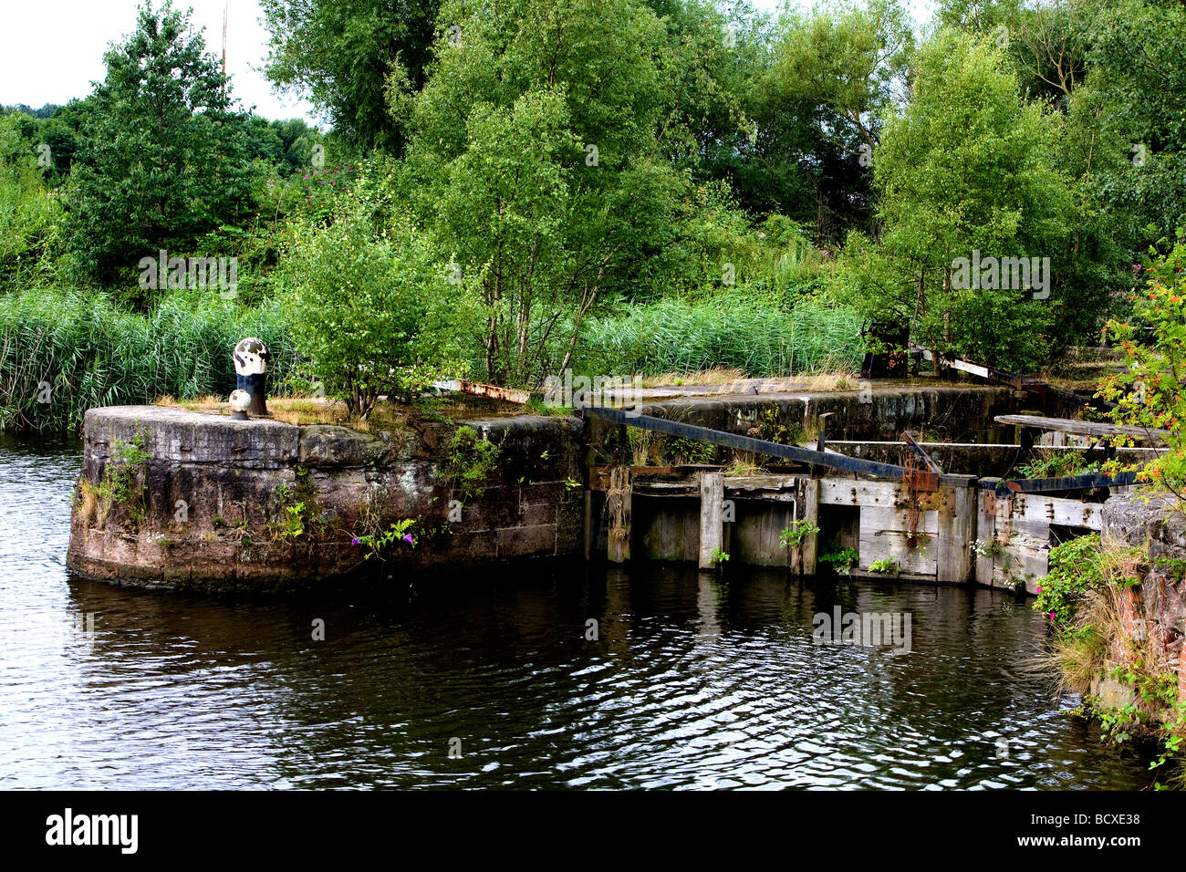 Lock gates, unused and deteriorating amongst the trees and weeds, along ...
