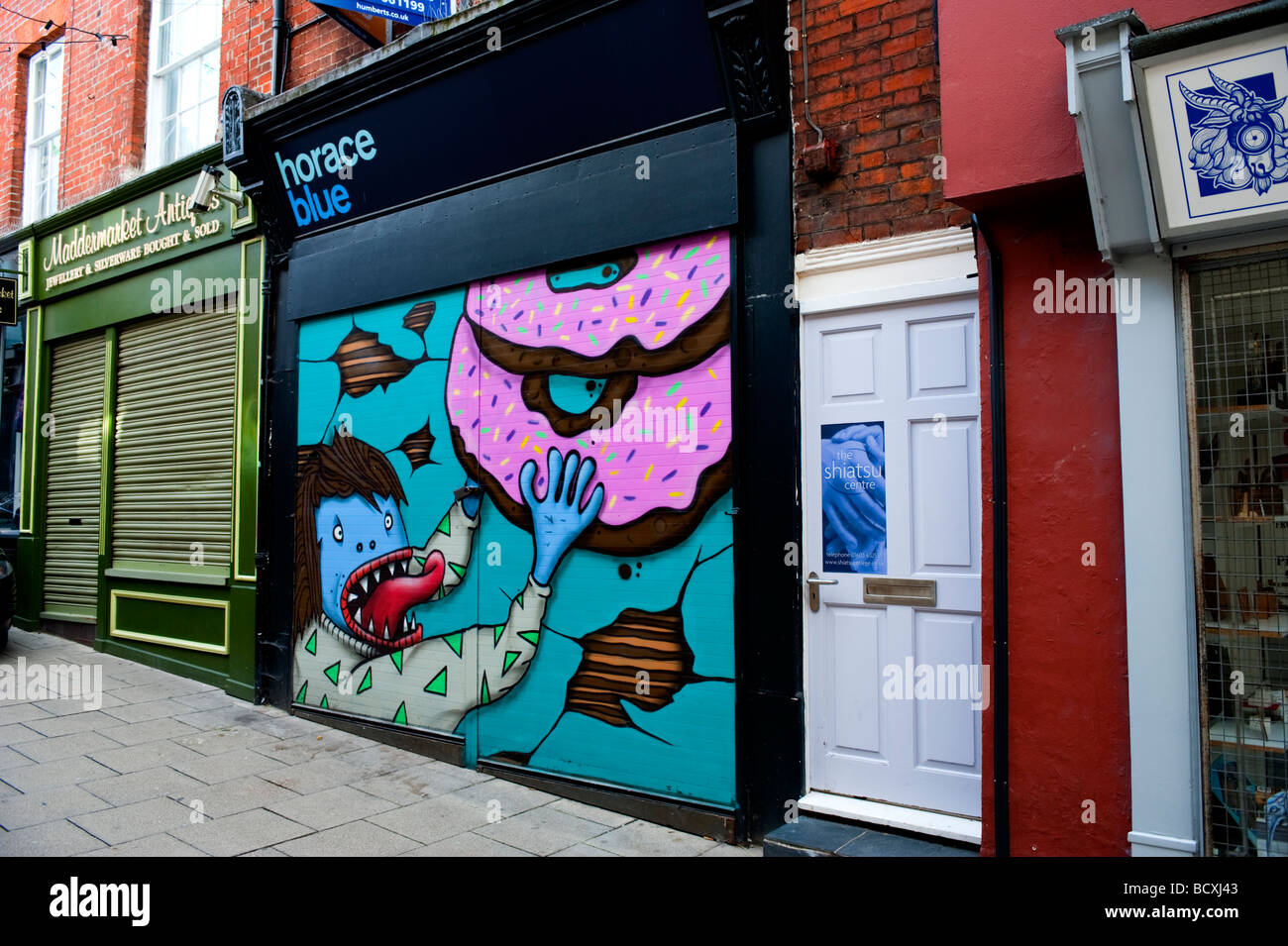 A shop front with a colourful murial on the blind Stock Photo - Alamy