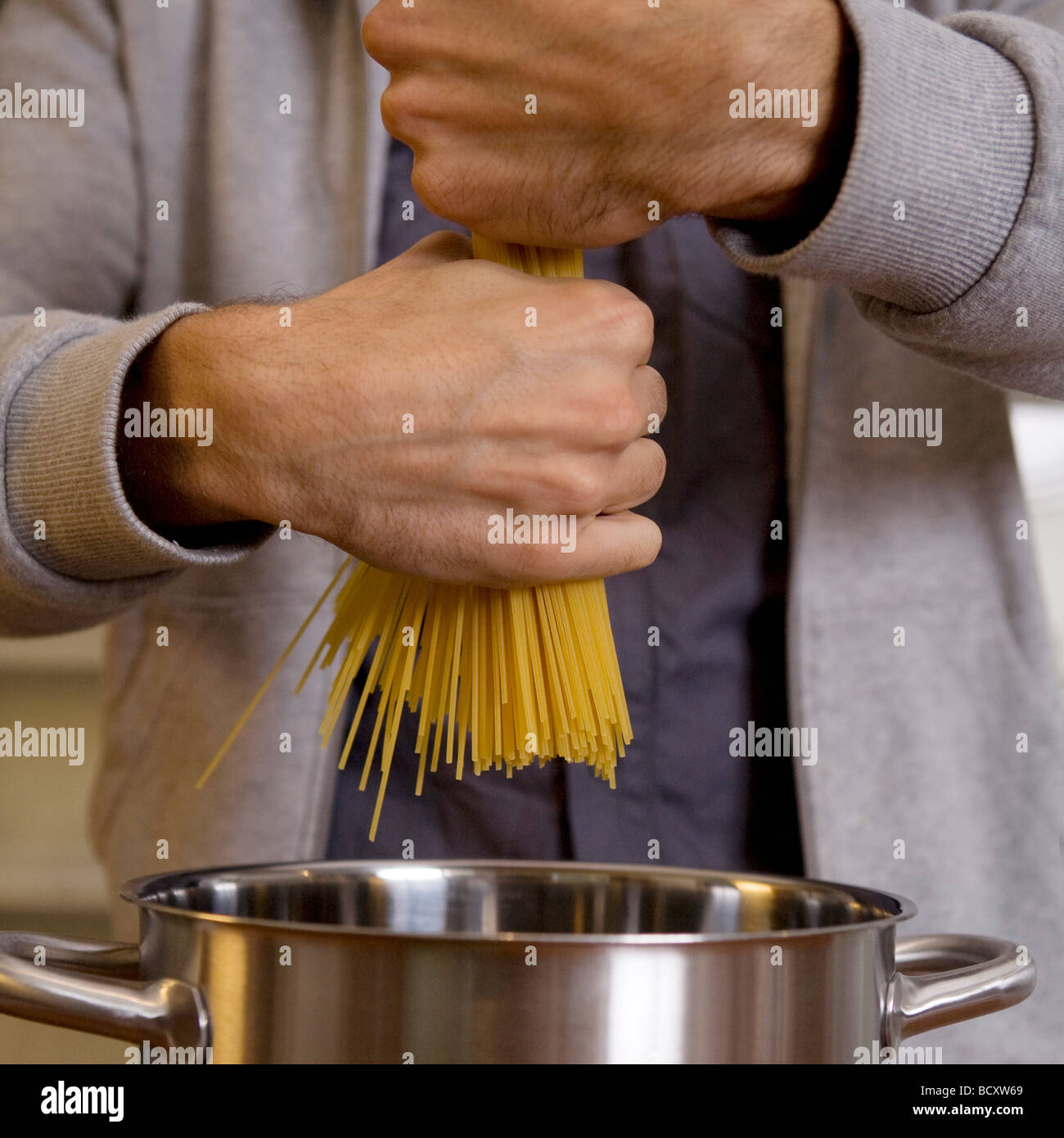 man holding spaghetti over pot Stock Photo - Alamy