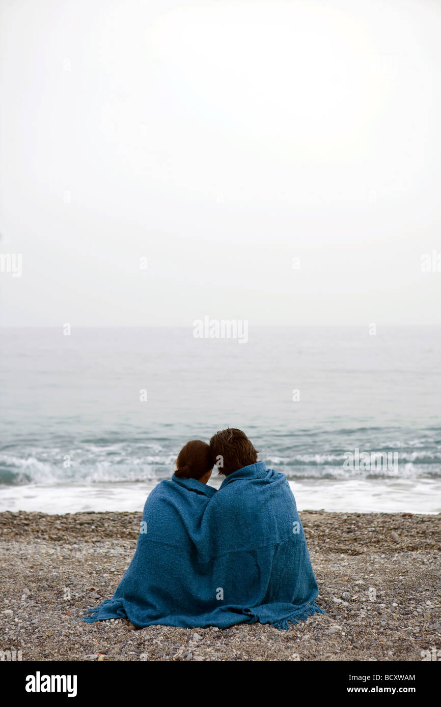couple wrapped in blanket at beach Stock Photo - Alamy