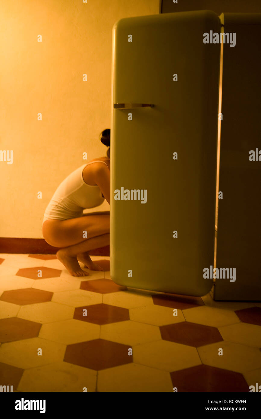 young woman looking inside fridge at night Stock Photo - Alamy