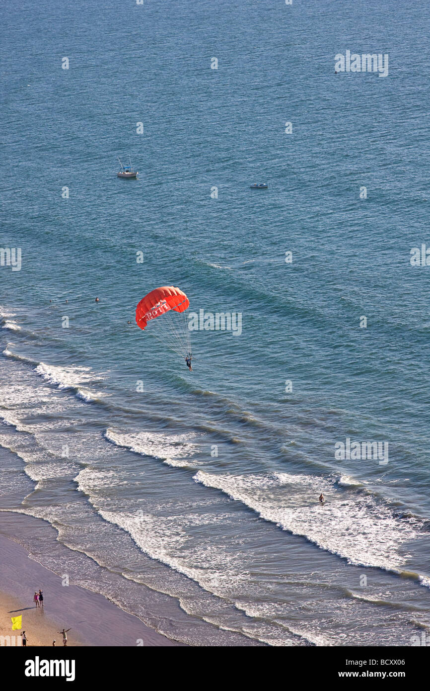 Parasailer and walking people seen in aerial view of the beach near the ...