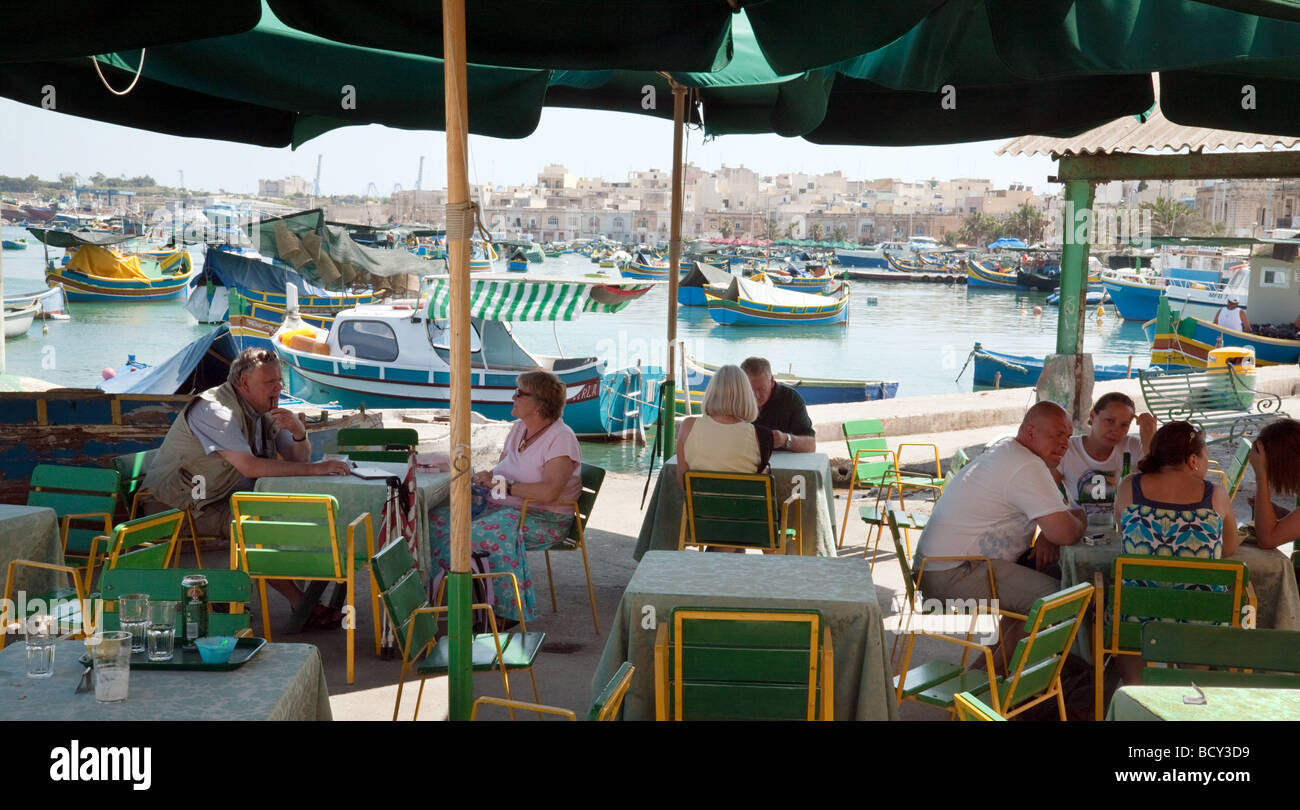 tourists drinking at a bar in the fishing harbour of Marsaxlokk, Malta ...