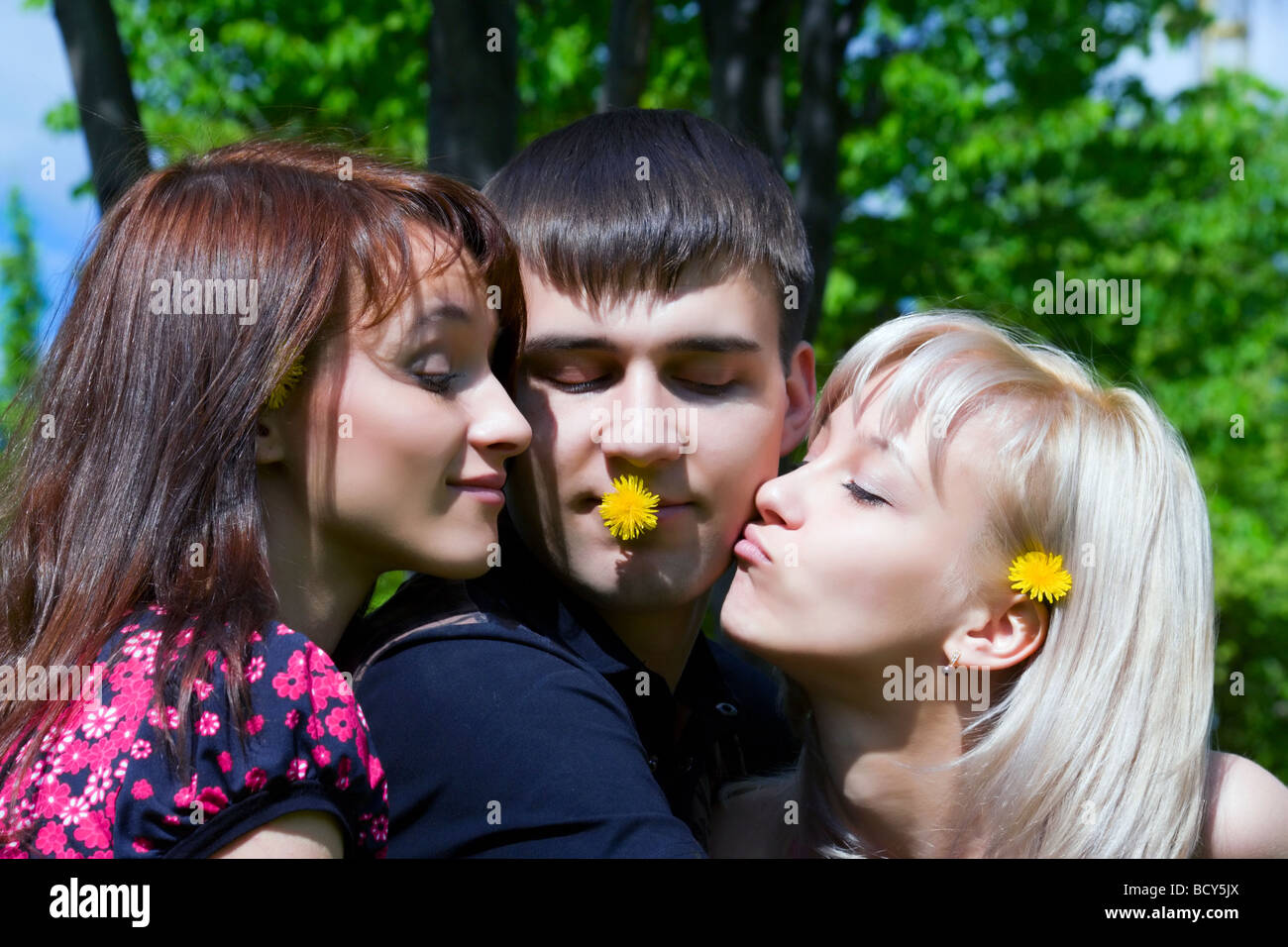 Happy young friends kissing on the nature Stock Photo - Alamy