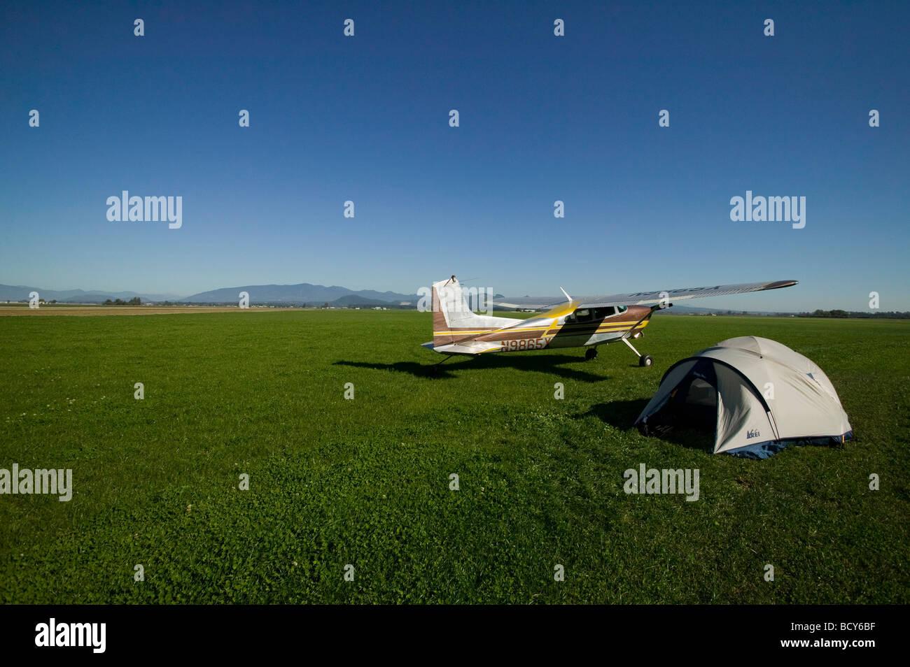 Small airplane parked on grass with tent beside Stock Photo - Alamy