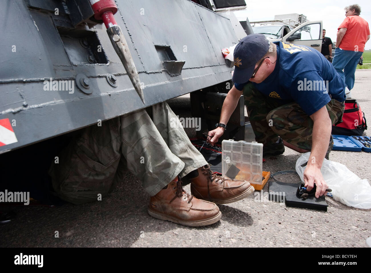 Storm chaser Sean Casey under car repairs the underside of the Tornado ...