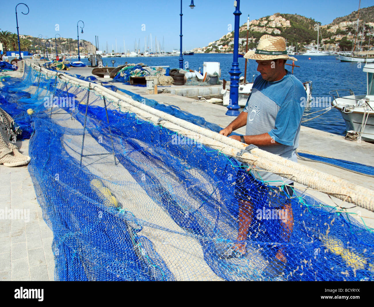 A fishermen mending his nets on the harbour side Stock Photo - Alamy