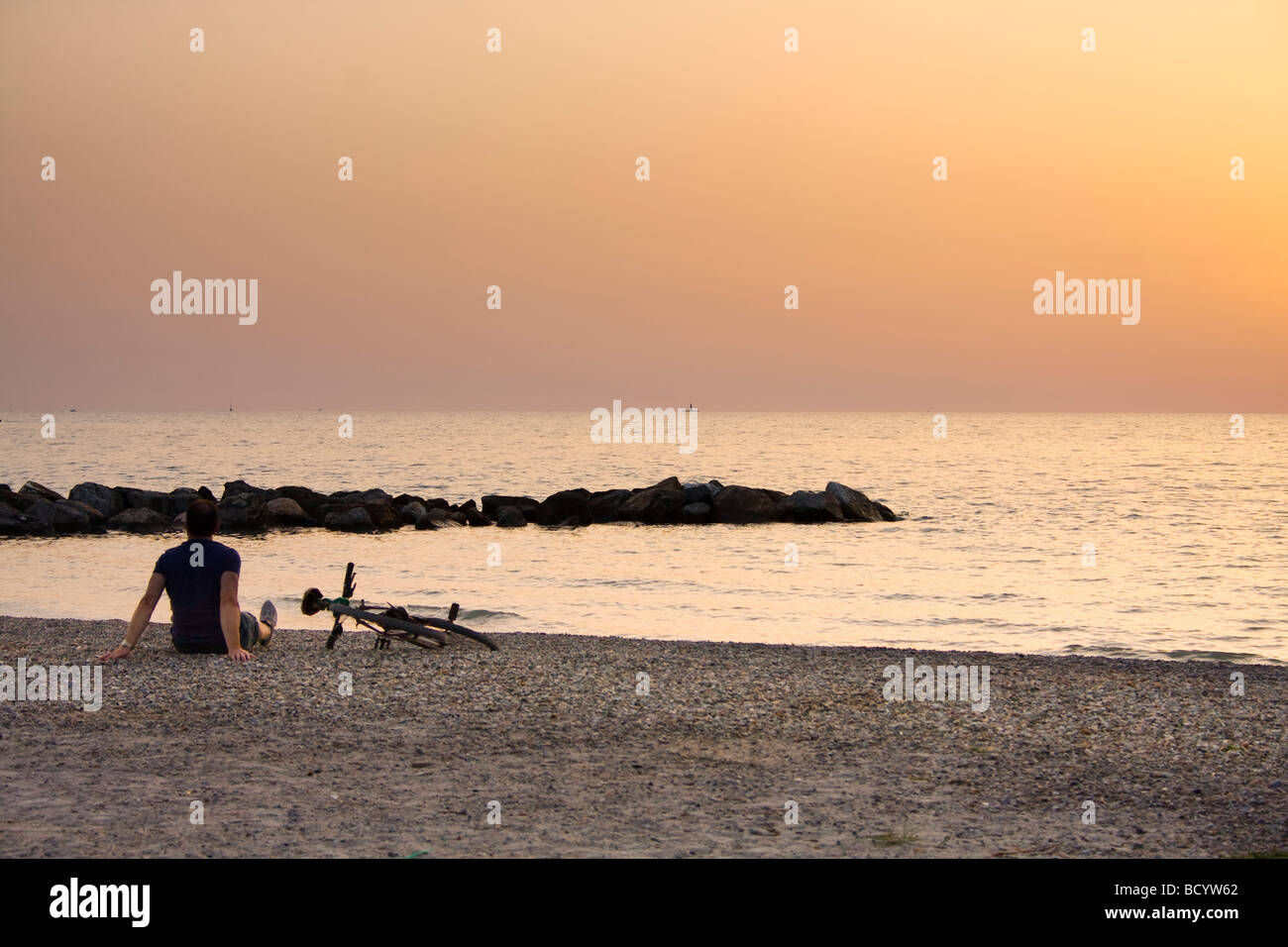 man sitting on beach facing the sea Stock Photo - Alamy