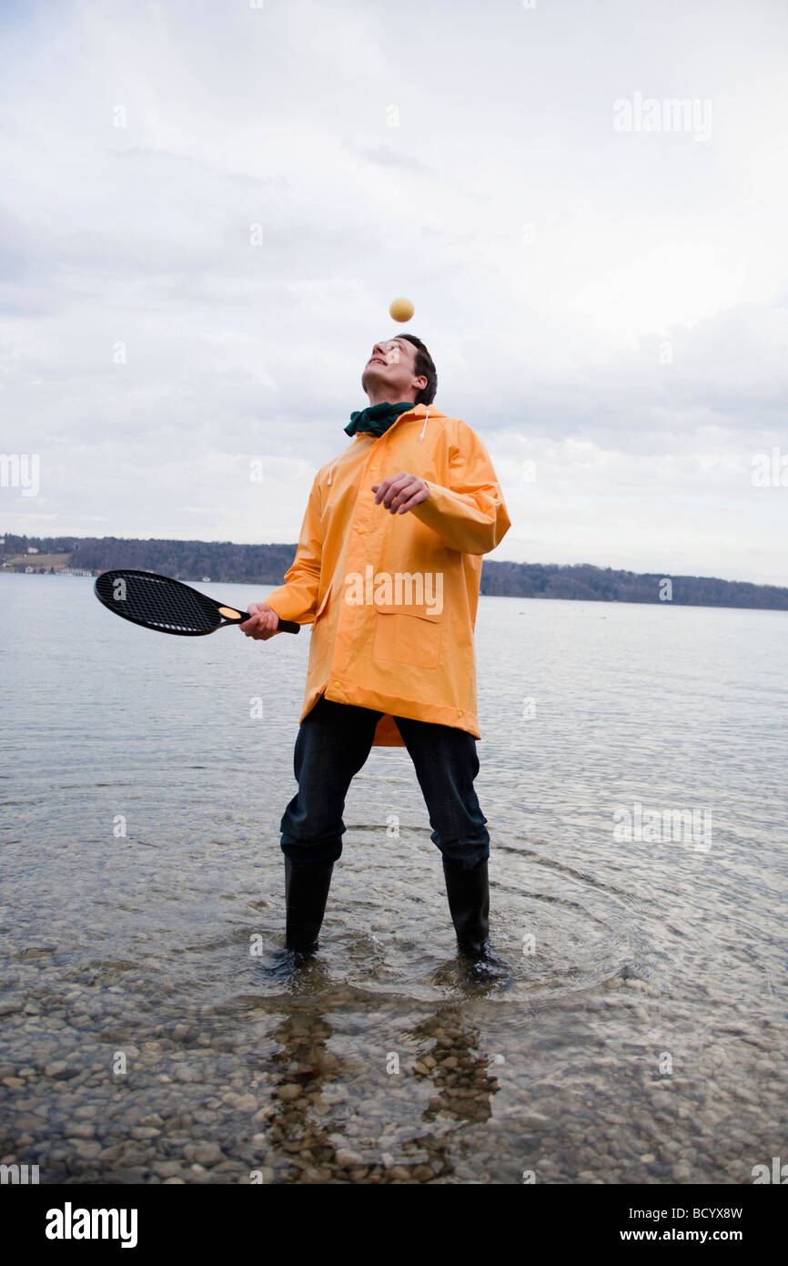 man in raincoat with racket and ball Stock Photo - Alamy