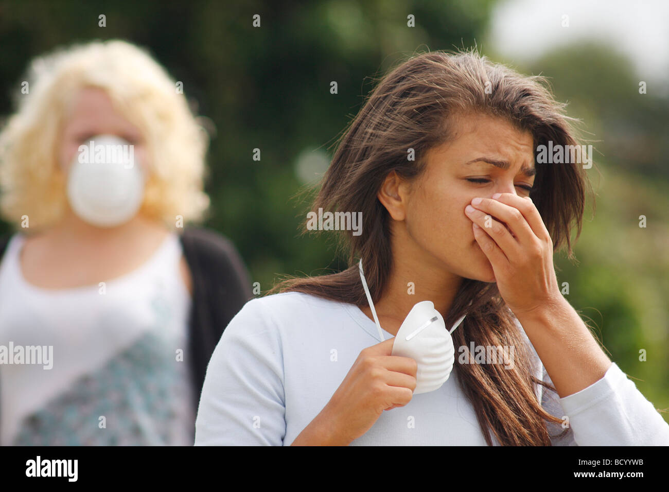 two women in street wearing filter masks one sneezing Stock Photo - Alamy