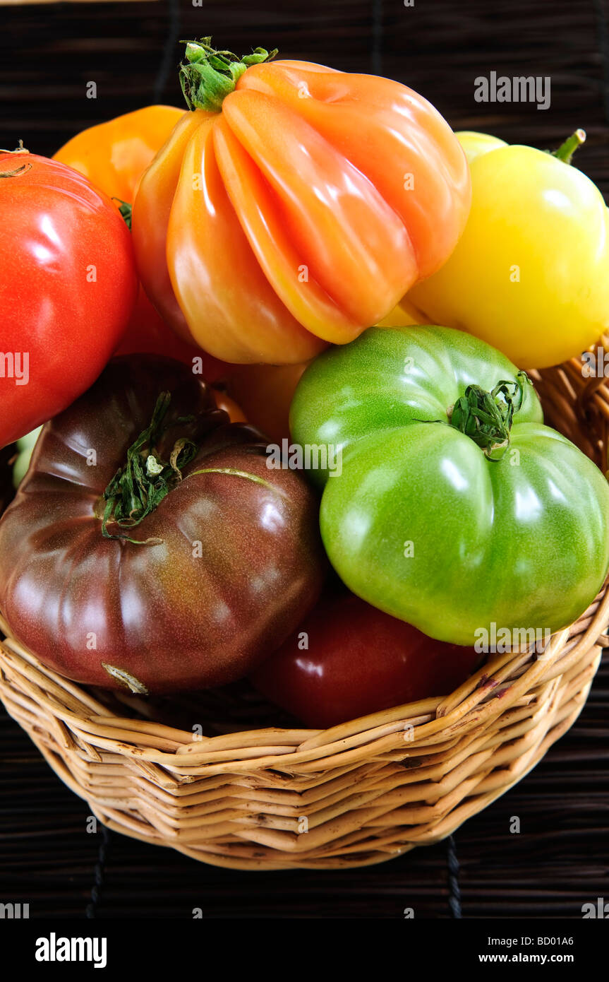 Wicker basket full of multi colored heirloom tomatoes Stock Photo - Alamy