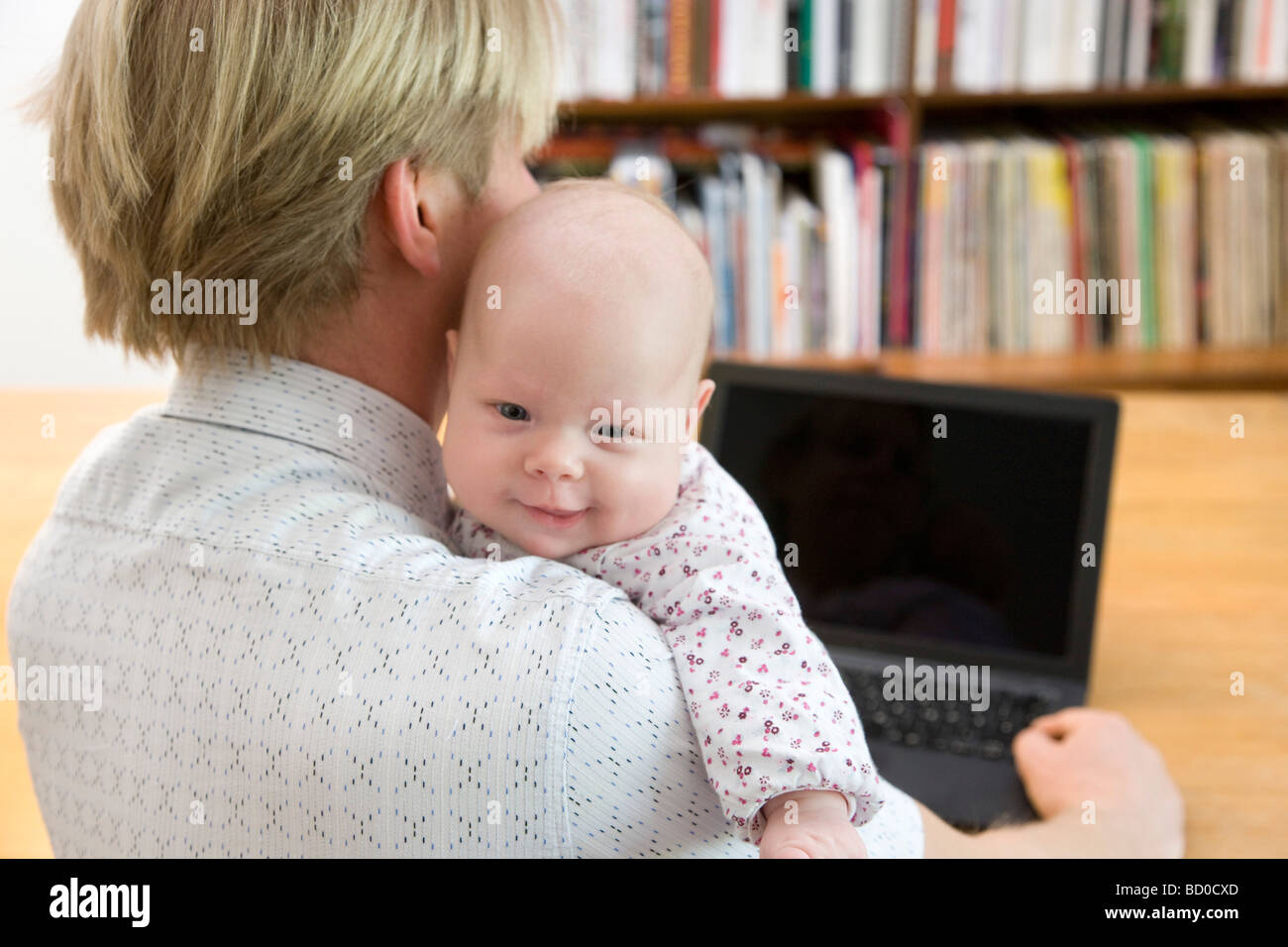 father working on laptop carrying baby Stock Photo - Alamy