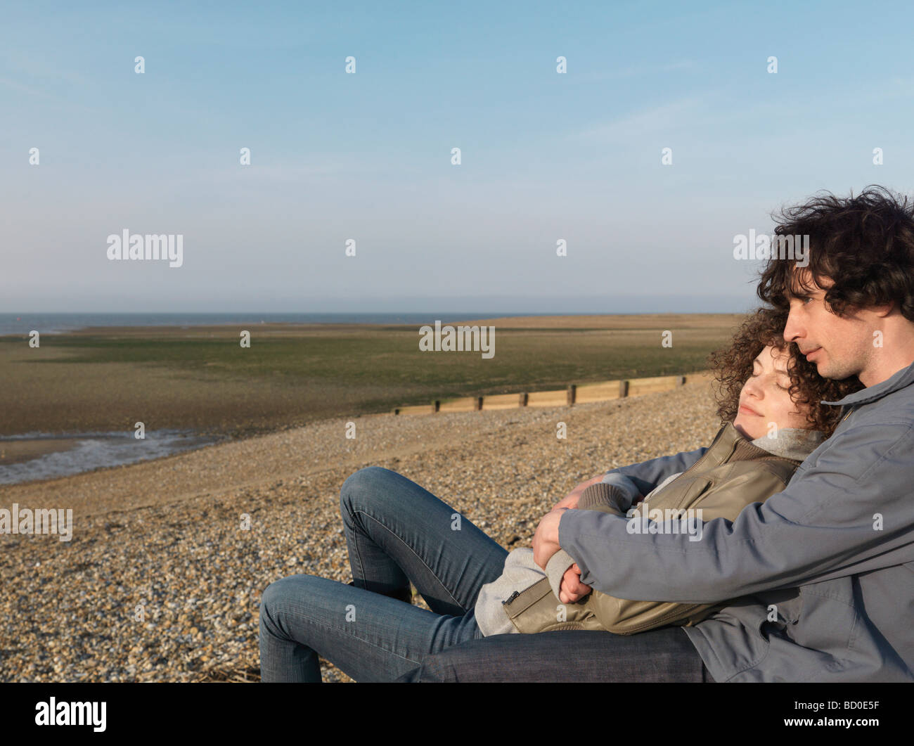 Couple cuddling on pebbled beach Stock Photo - Alamy