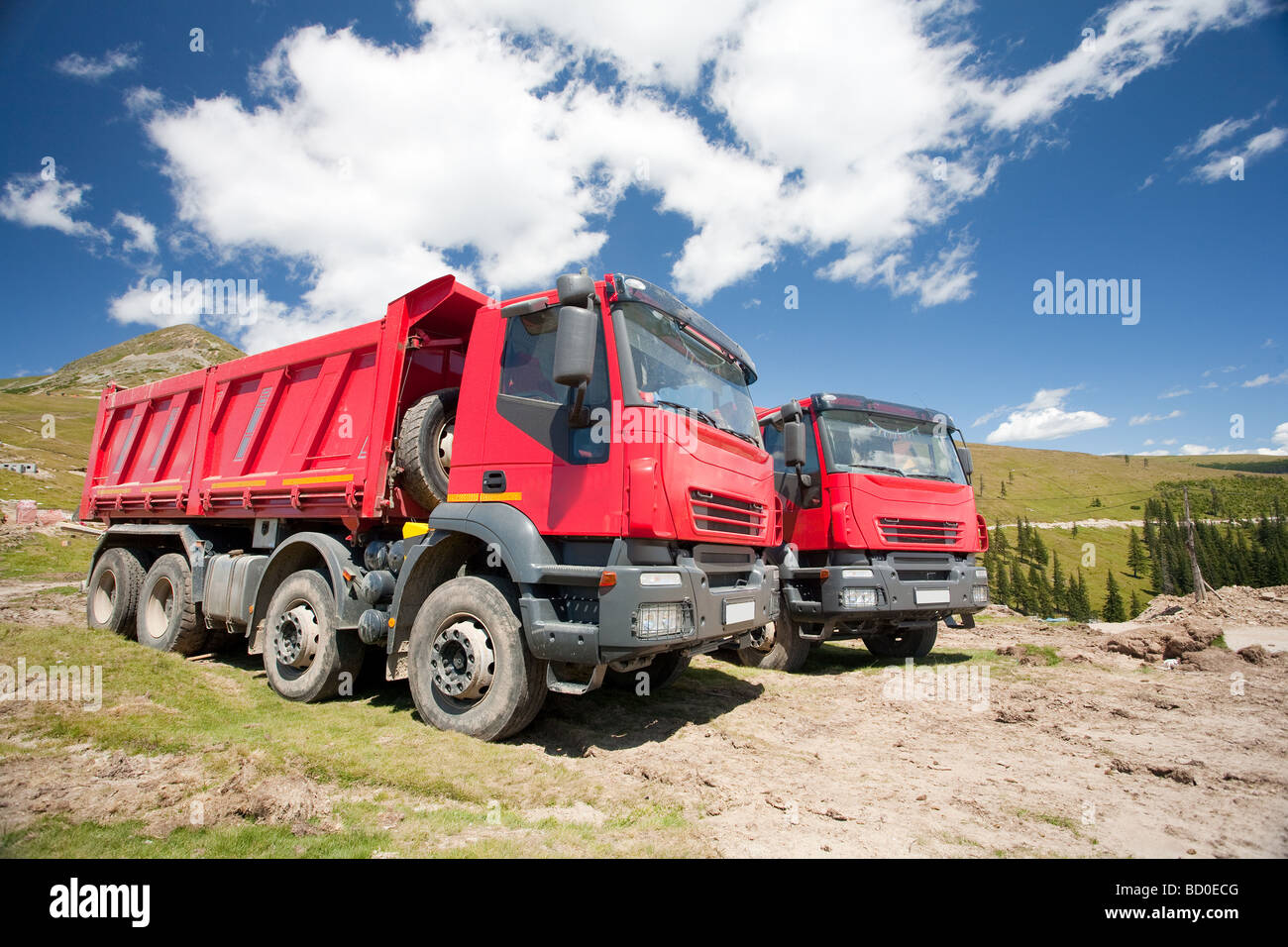 Two large red dump trucks at construction site in a sunny summer day ...